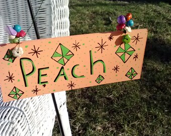 garden sign,"peach" peach color and green, 7 inches by 2 and 3/4 inches